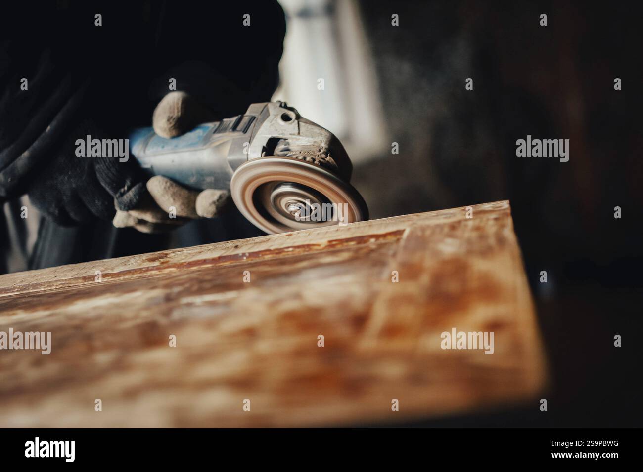 Close-up of a carpenter using a grinder on wood, creating dust and ...