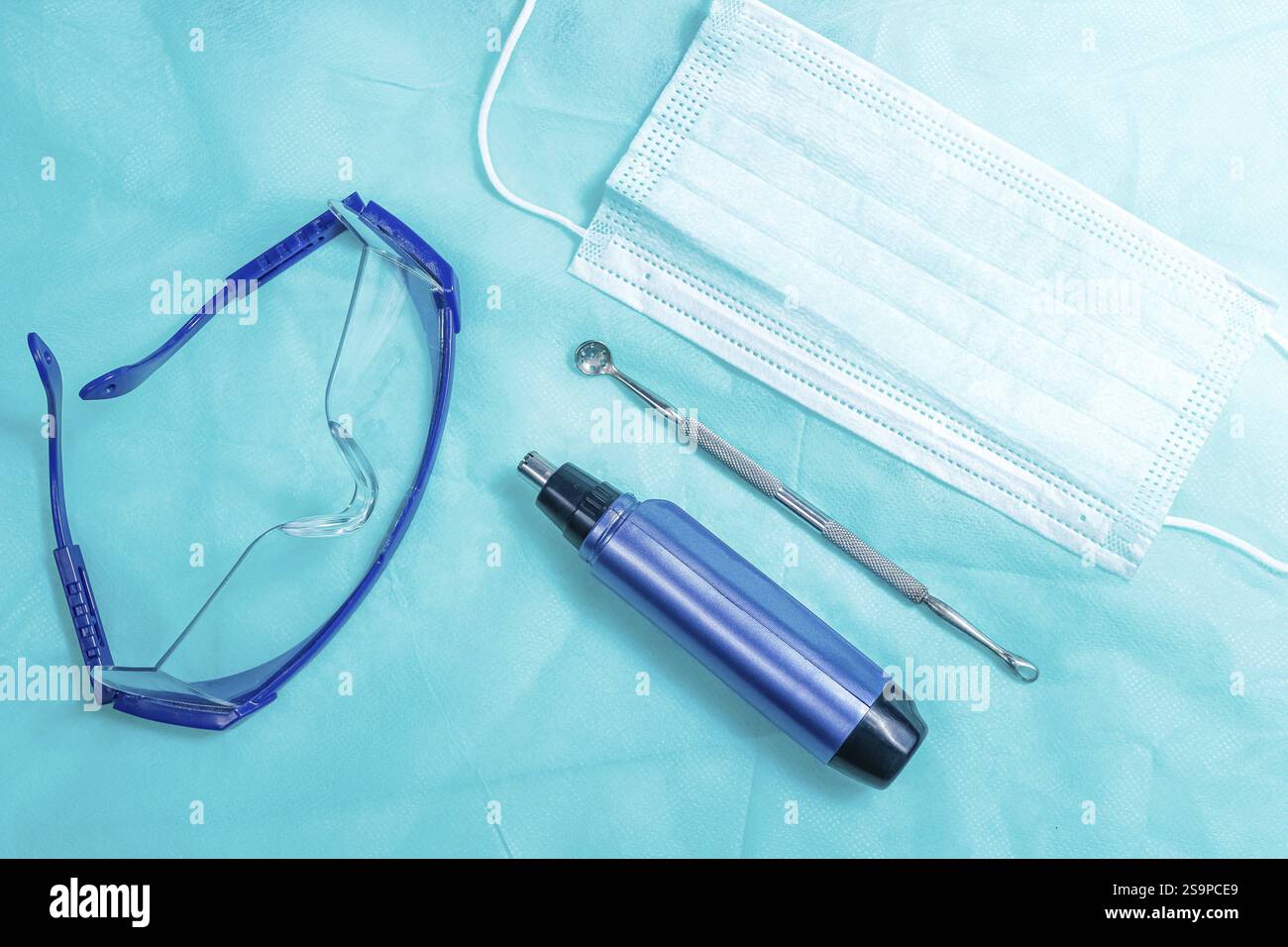 A surgical mask, protective glasses, and dental instrument on a blue ...
