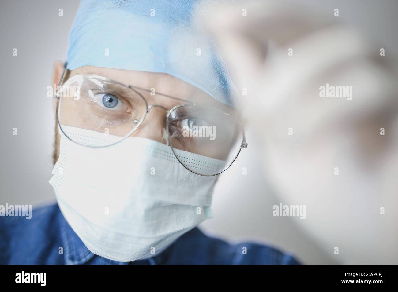 Medical professional with a focused gaze, wearing a mask and glasses in ...