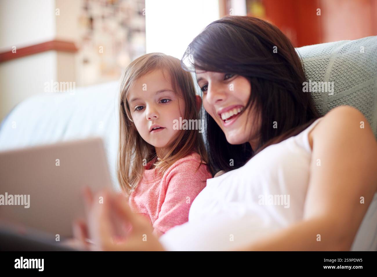 Tablet, elearning and mom with child on sofa in living room for ...
