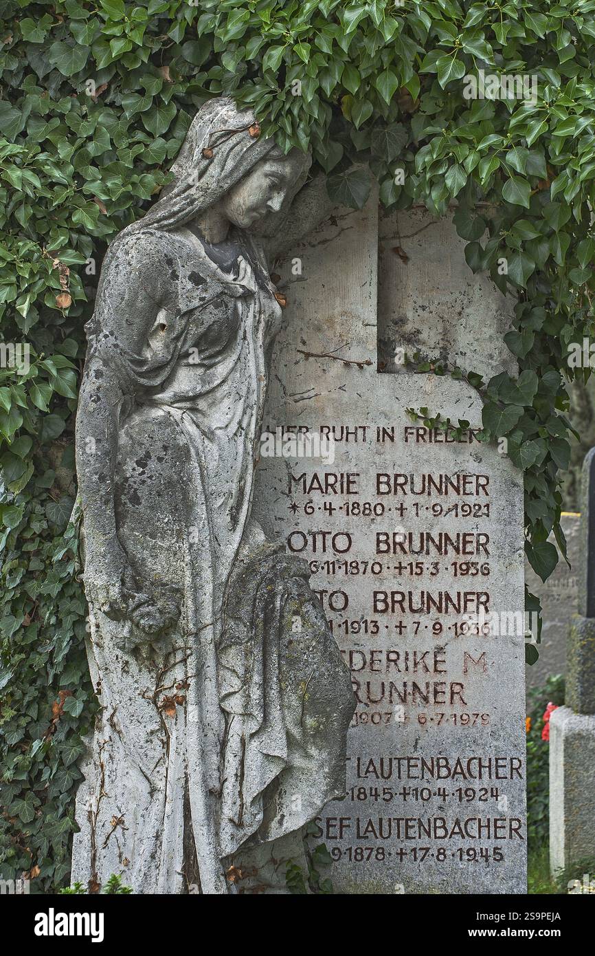 Gravestone with mourning female figure and overgrown with traveller's ...