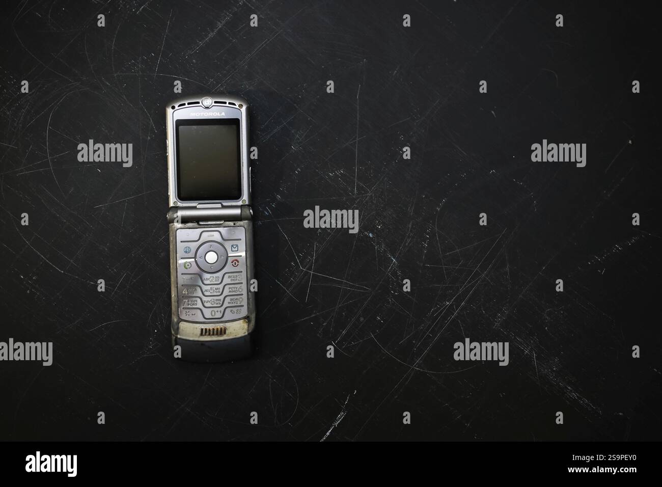 A silver flip phone fully open on a scratched dark surface Stock Photo ...