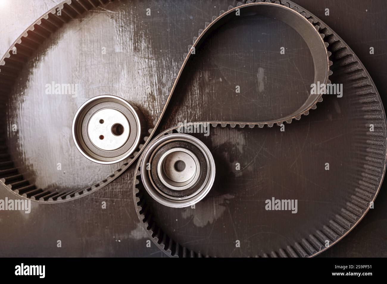 Timing belt and gears arranged on a black surface with lighting from ...