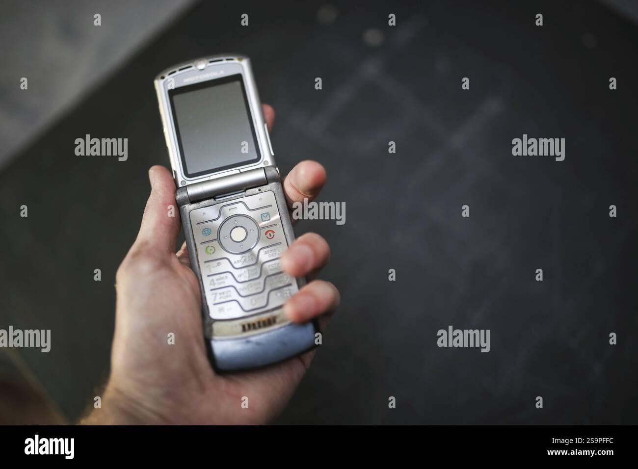 A hand holding a silver Motorola RAZR flip phone, displayed open Stock ...
