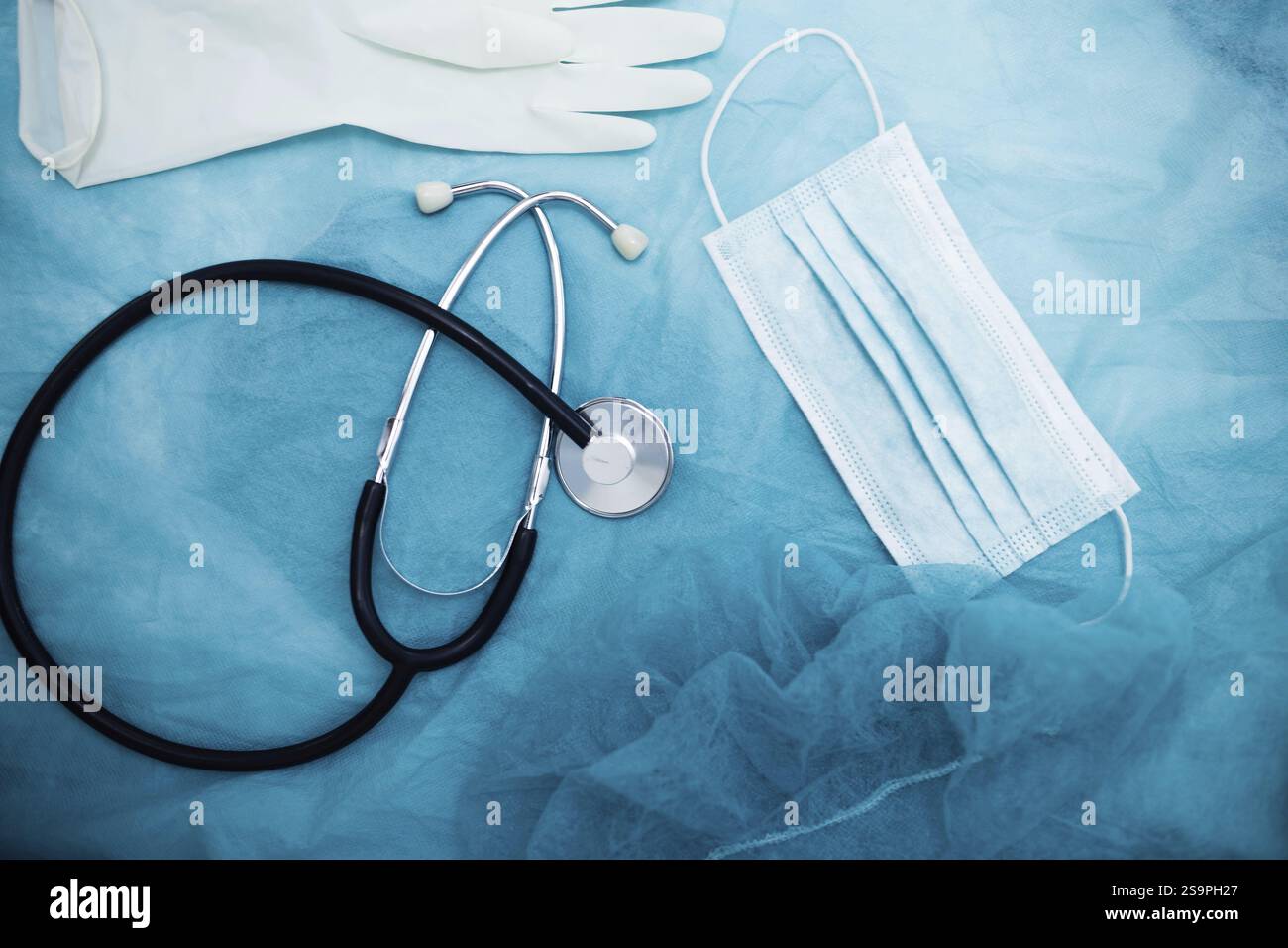 Stethoscope and face mask with gloves on blue material, medical setup ...