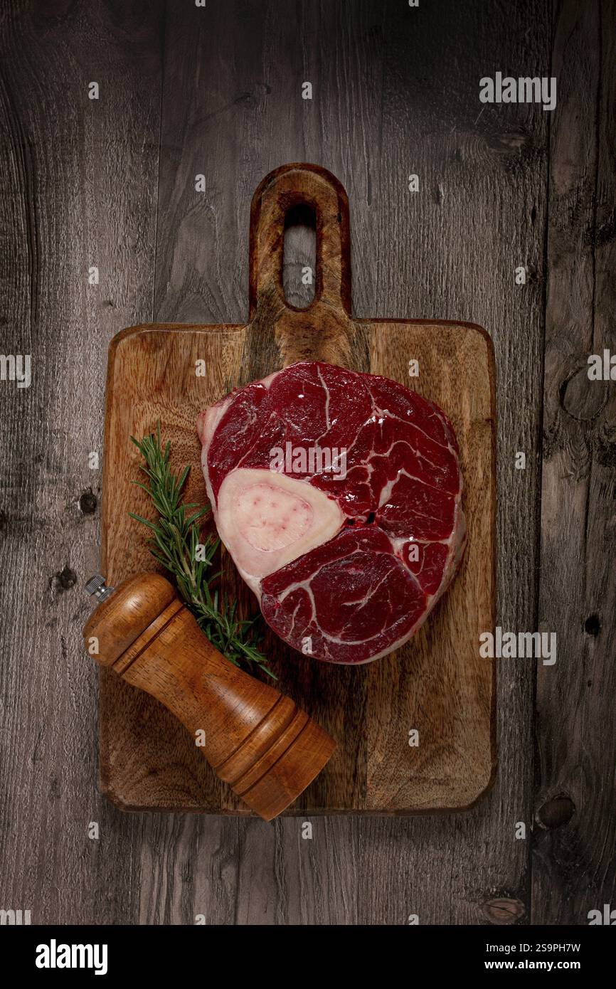 A shank on the bone, raw meat for ossobuco, on a wooden chopping board ...