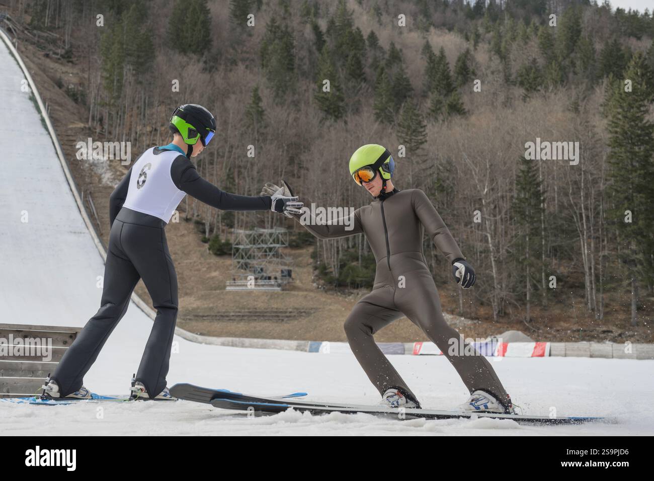 Two happy male ski jumpers giving high five in the outrun at a training ...
