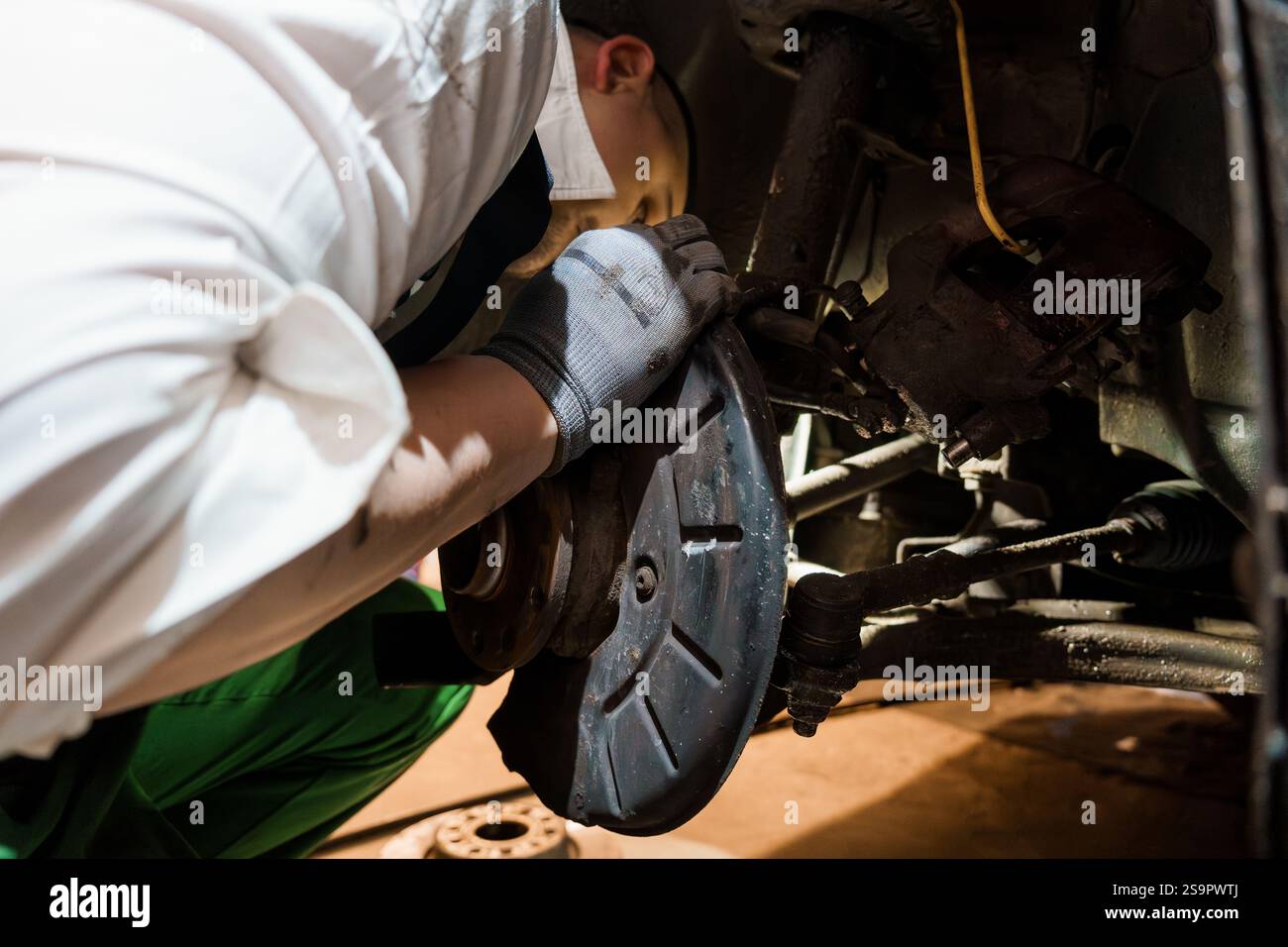 Mechanic Performing Brake Inspection and Repair Underneath a Vehicle ...