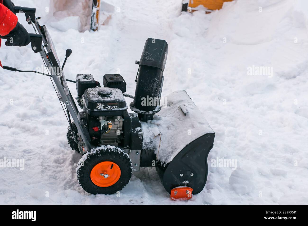 Closeup of red snow blower in action. Senior mature man outdoor in front of house using ...