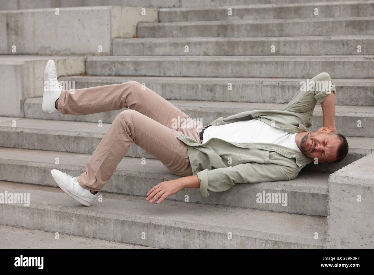 Man with injured head on stairs outdoors after fall. Dangerous accident ...
