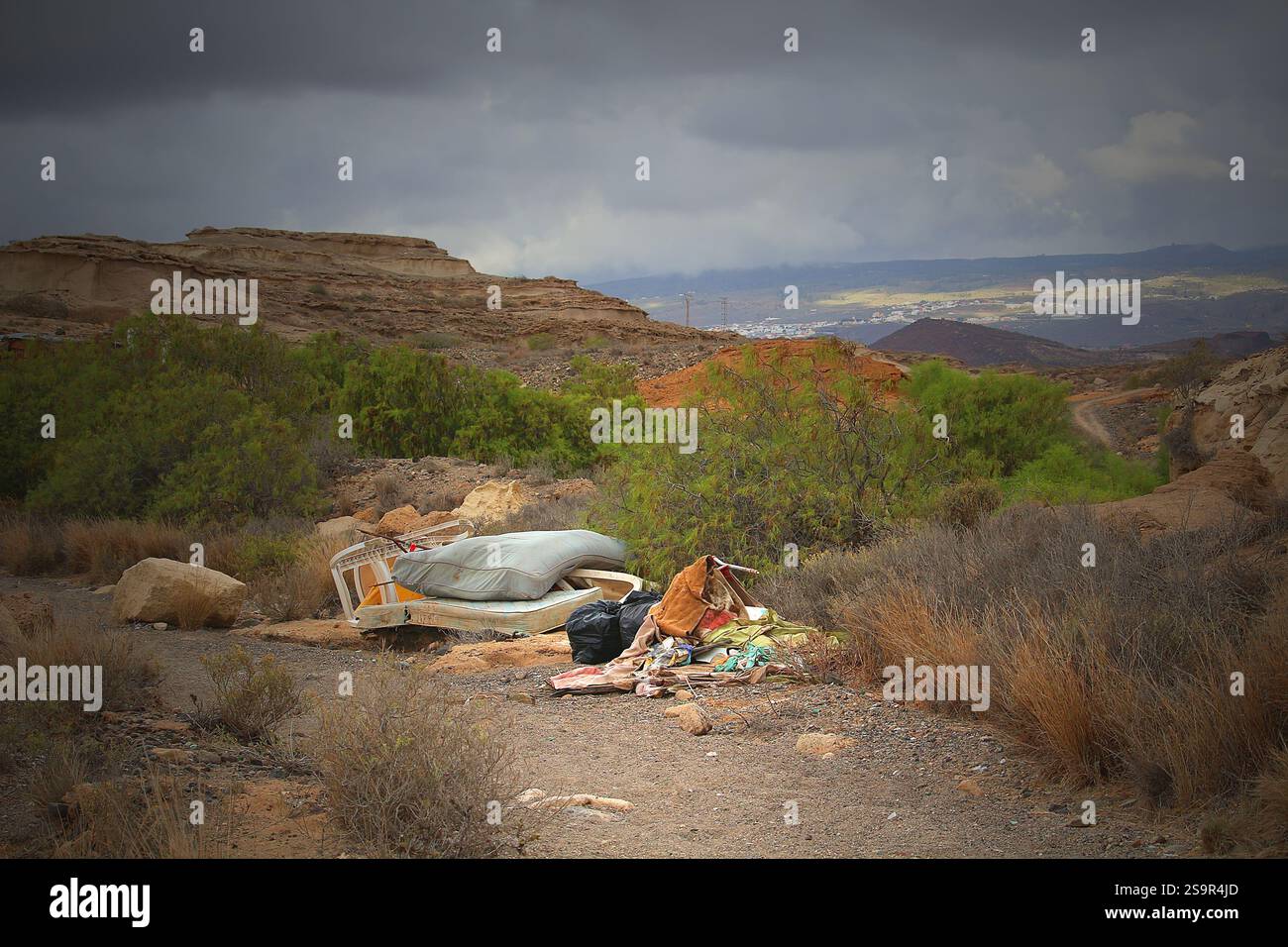 Waste dumped alongside a walking trail trough the arid landscape at the ...