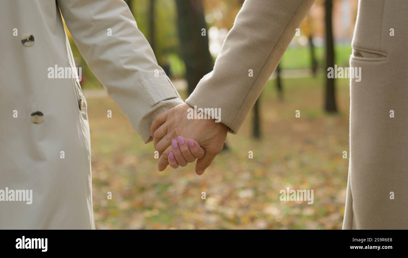 Close up holding hands couple together in park outdoors middle aged ...