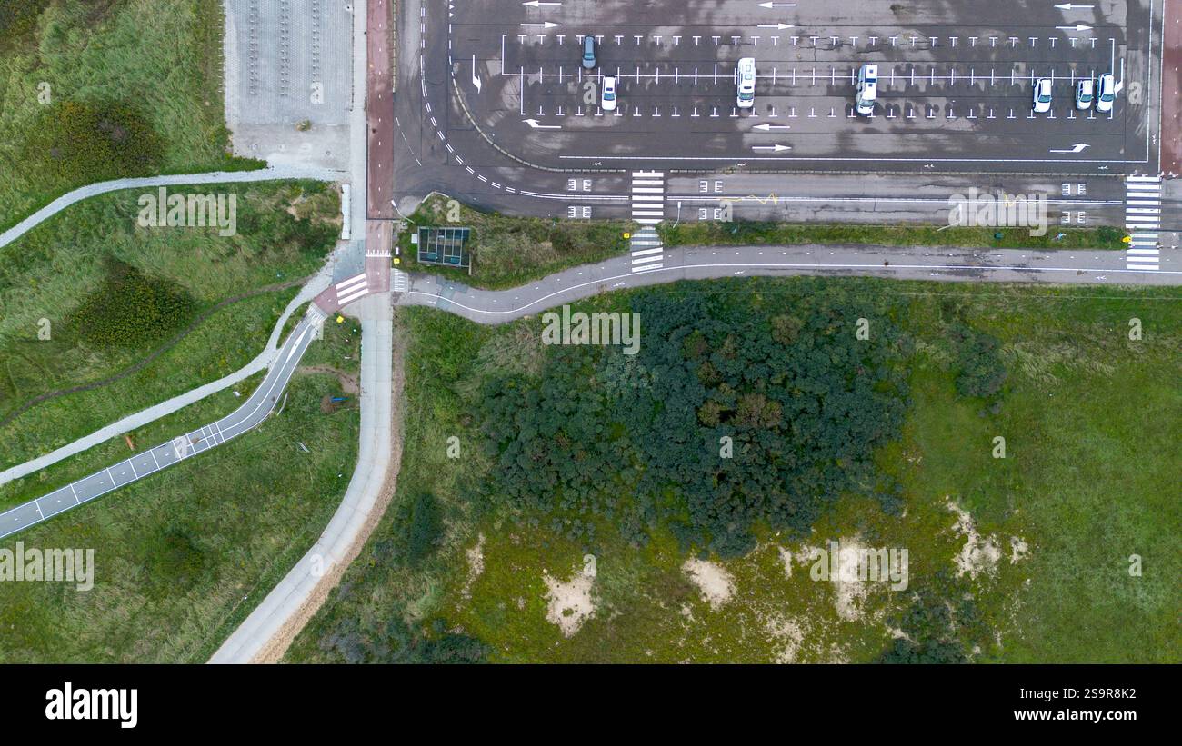 Aerial view of a parking lot with cars, crosswalks, paved roads, and ...