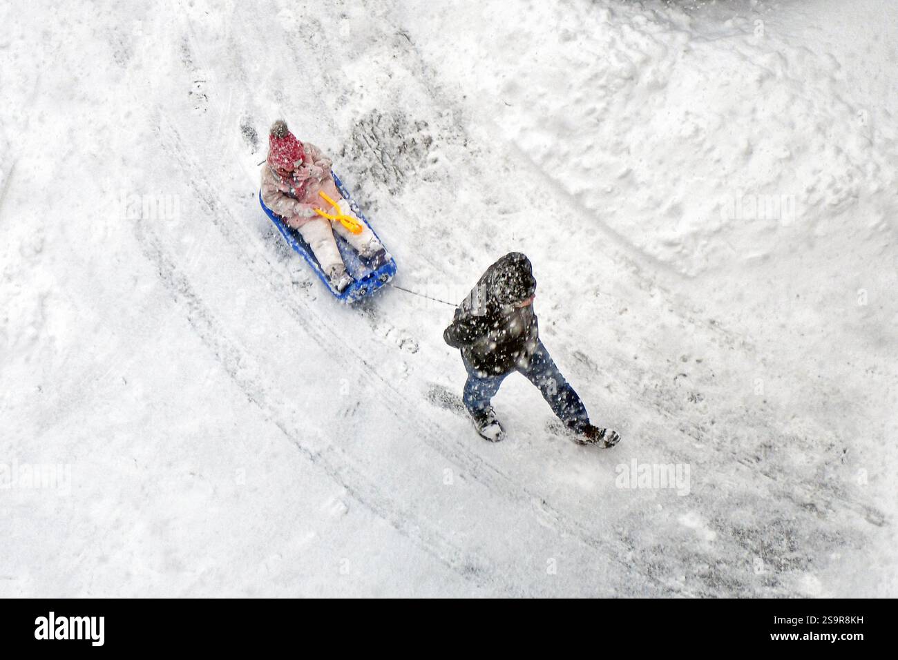 A man pulls his child on a sled on the snow-covered ground in Yantai ...