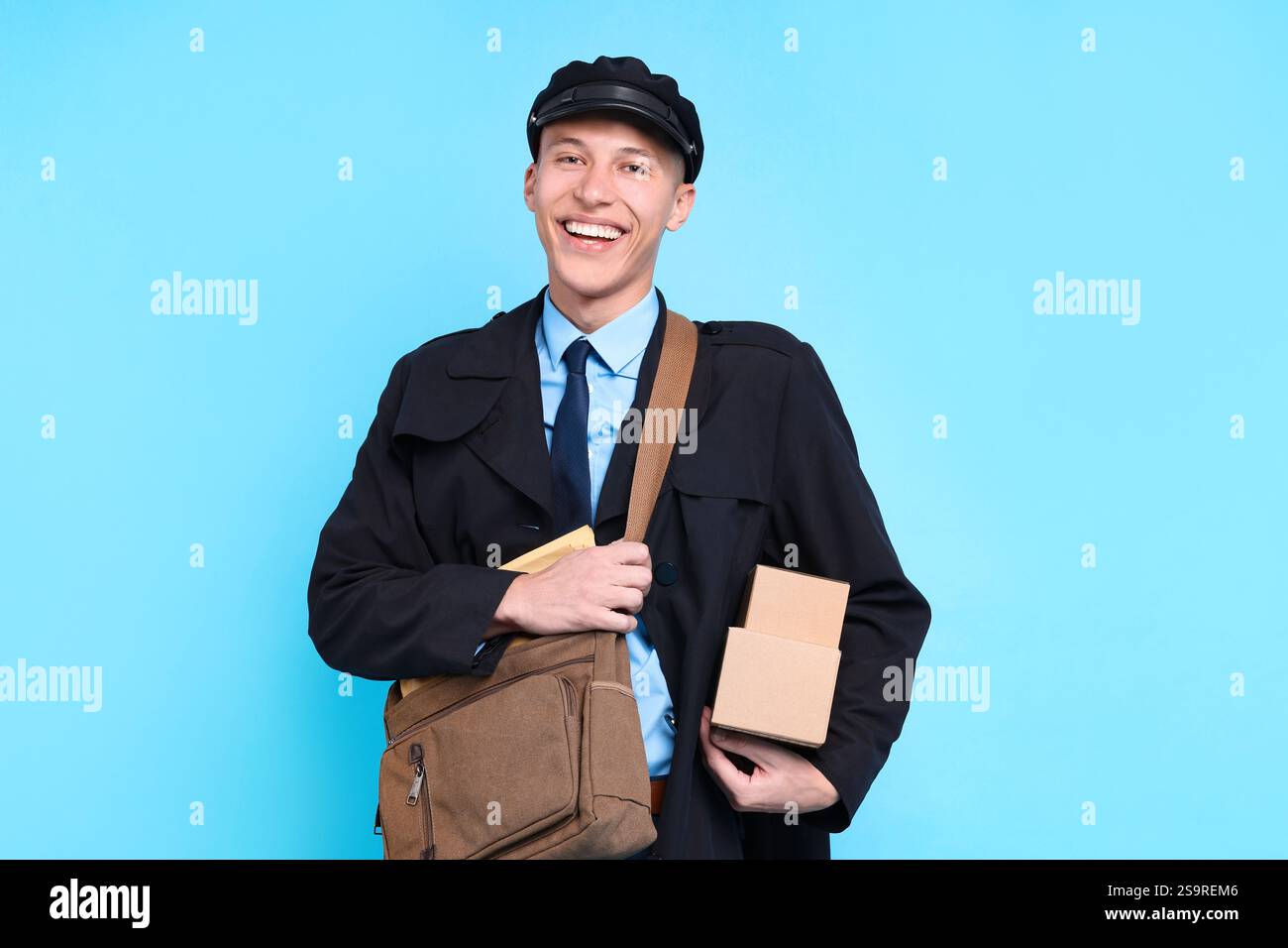 Happy postman with bag and parcels on light blue background Stock Photo ...