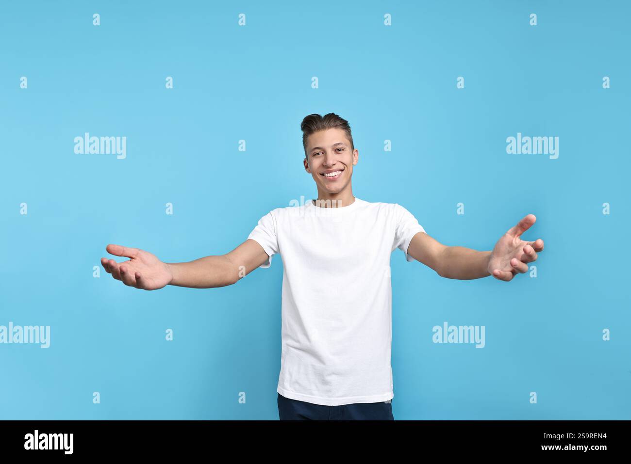Happy man welcoming friends or guests on light blue background Stock ...