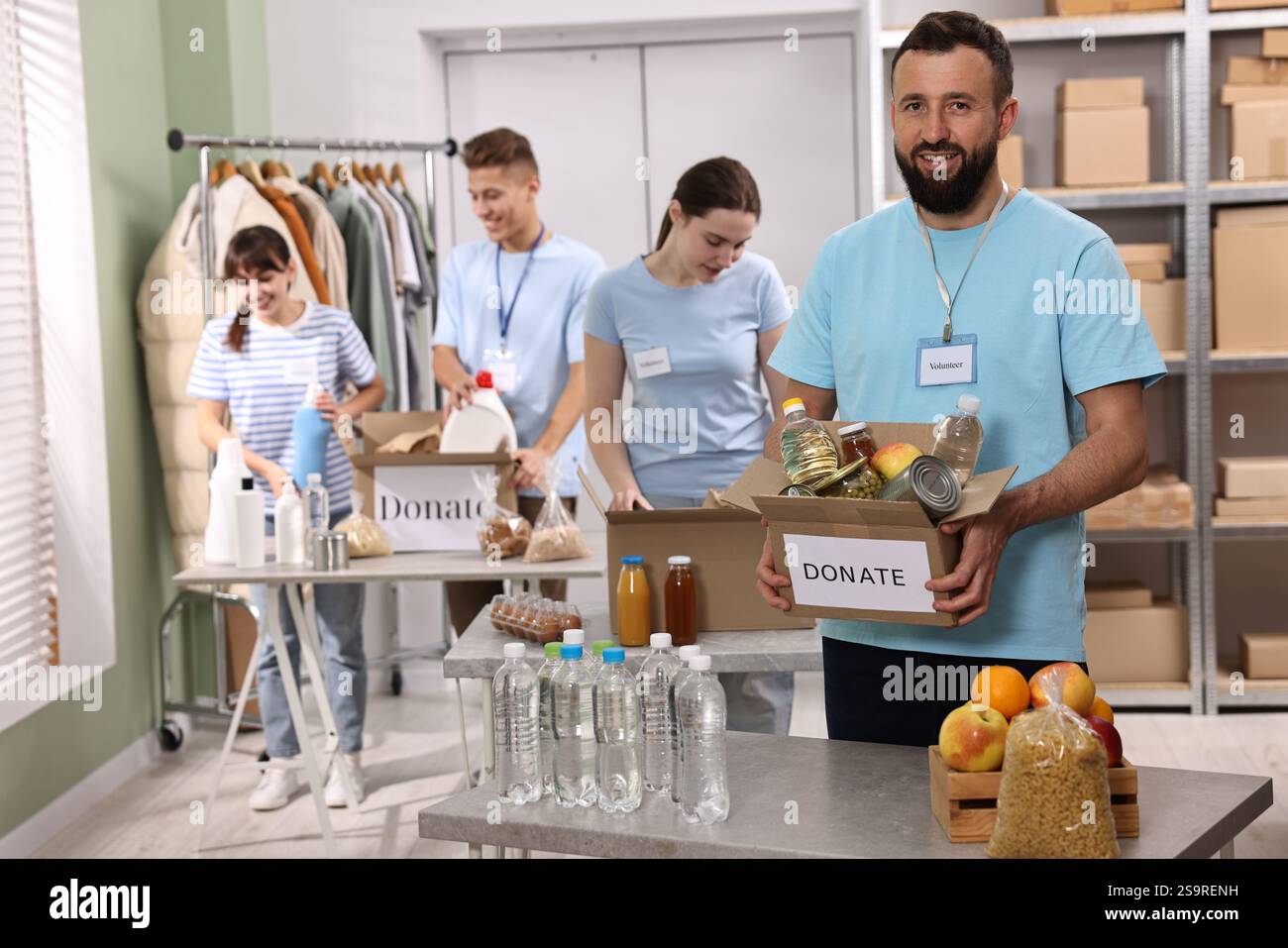 Group of volunteers packing donation goods at tables indoors Stock ...