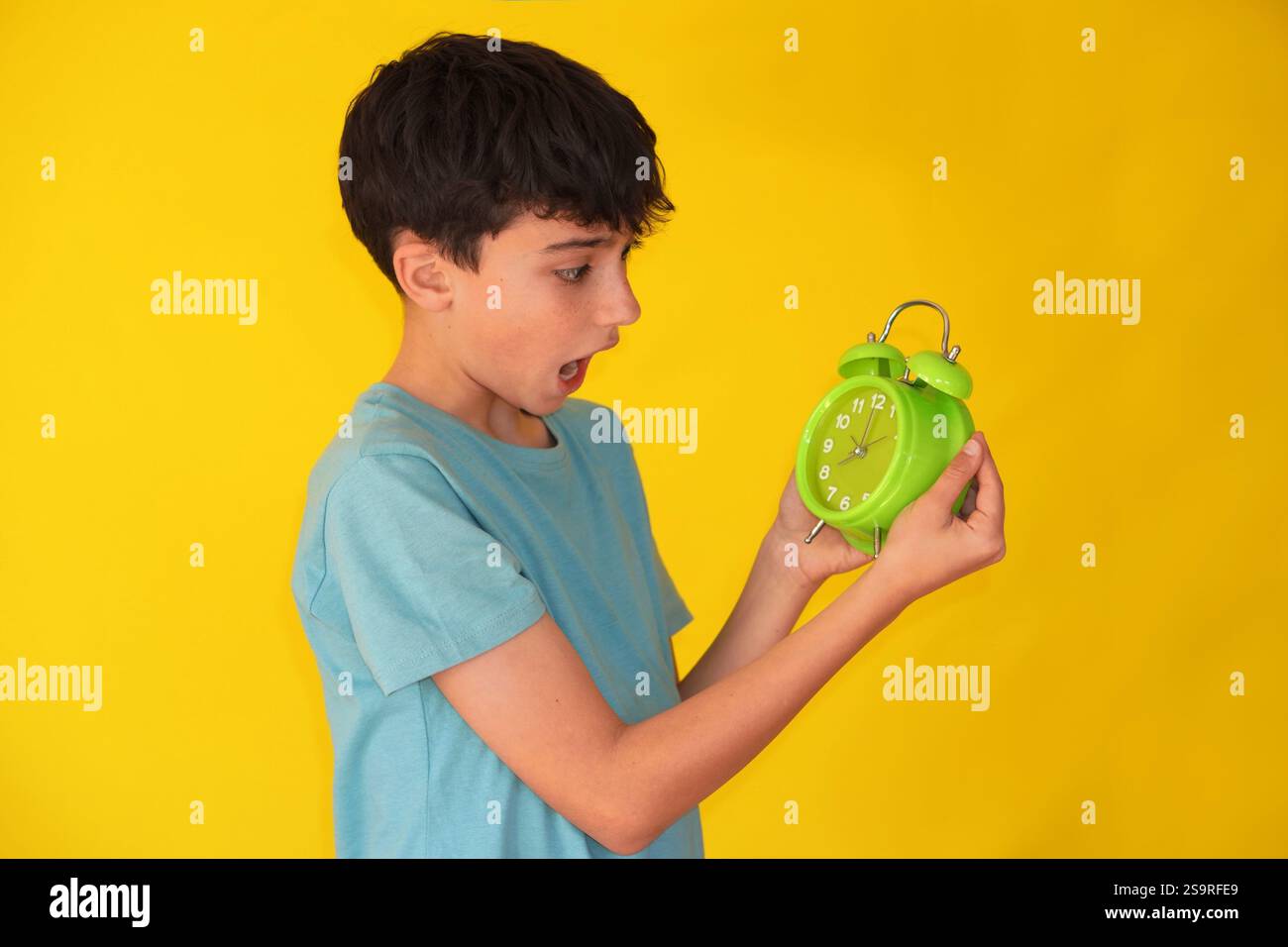 child preteen with an alarm clock in his hands and gesture of surprise ...