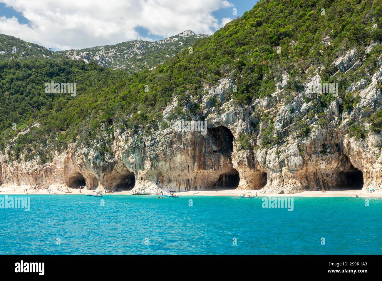 People in the caves of Cala Luna beach and clear transparent blue water ...