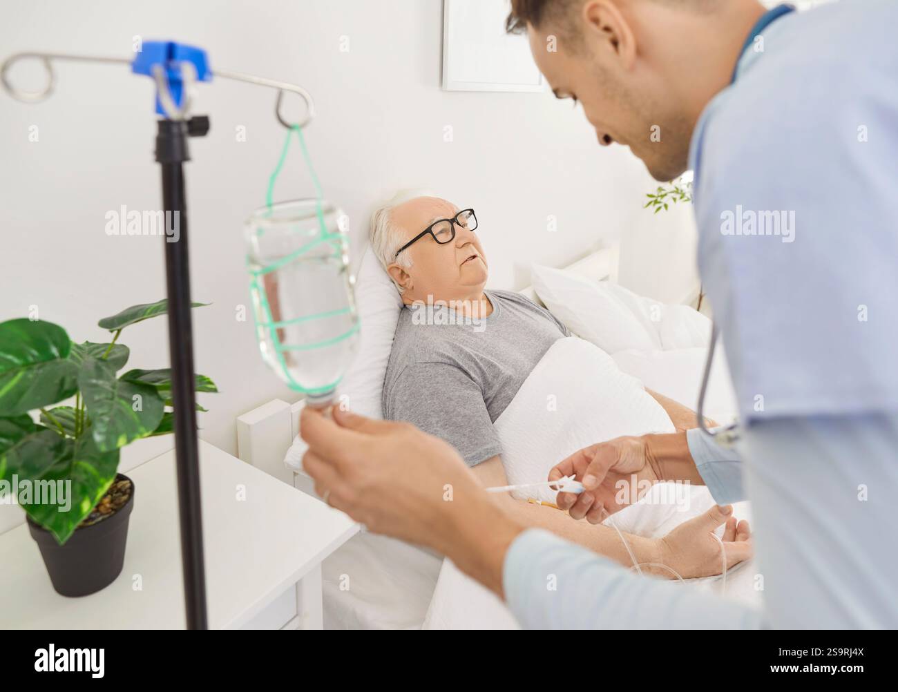 Nursing sick senior man with intravenous drip lying on medical couch in ...