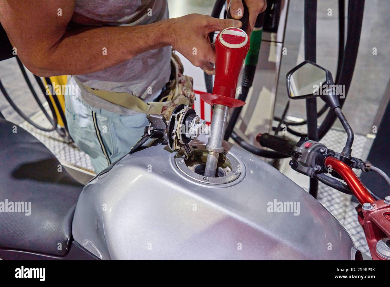 Man fueling motorcycle at gas station. Fuel connecting motorcycle and ...
