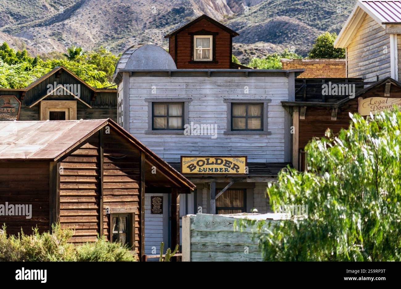 A rustic western town scene featuring wooden buildings with a sign that ...