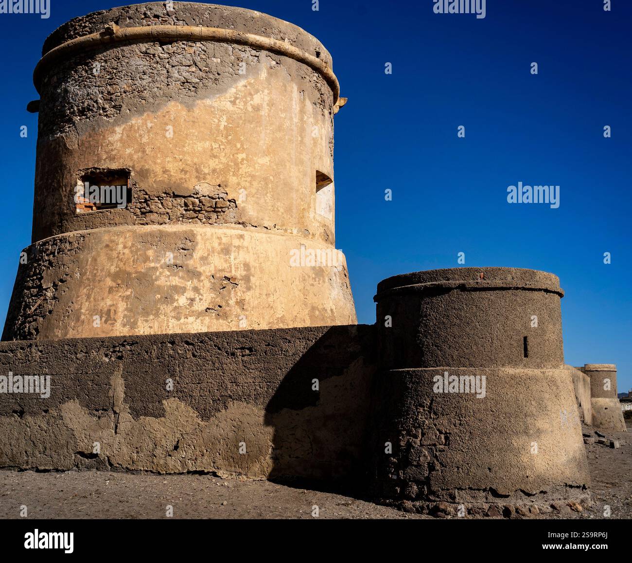 Two weathered stone towers stand against a clear blue sky, showcasing ...
