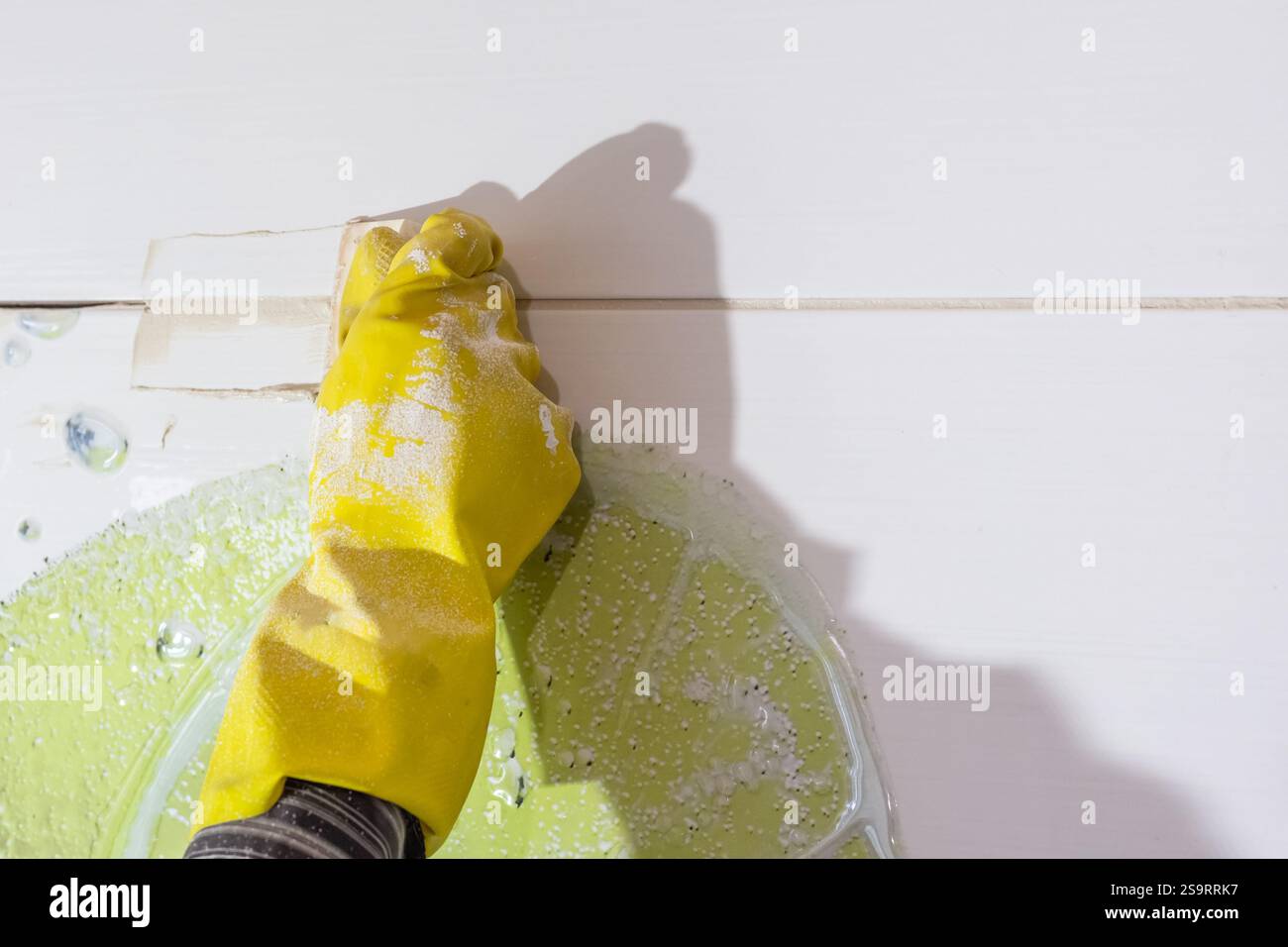 Laying ceramic tiles. The craftsman fills the tile joints with grout ...