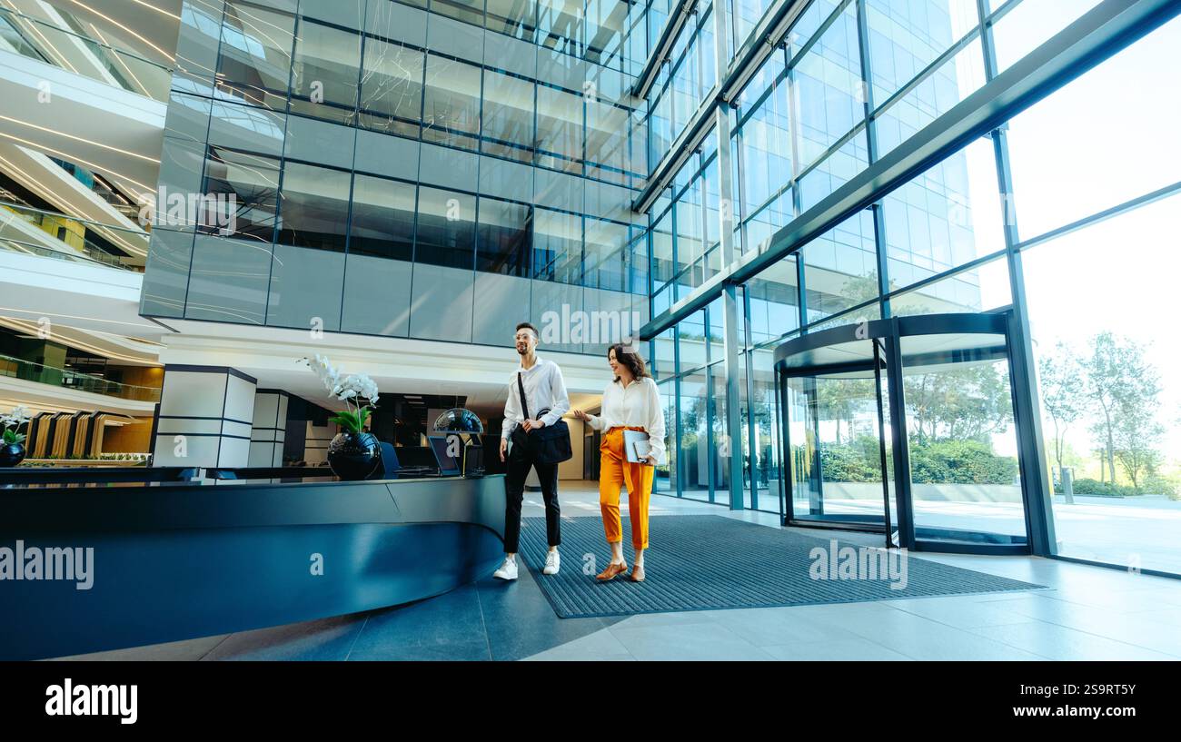 A contemporary office lobby with large glass windows, where two ...