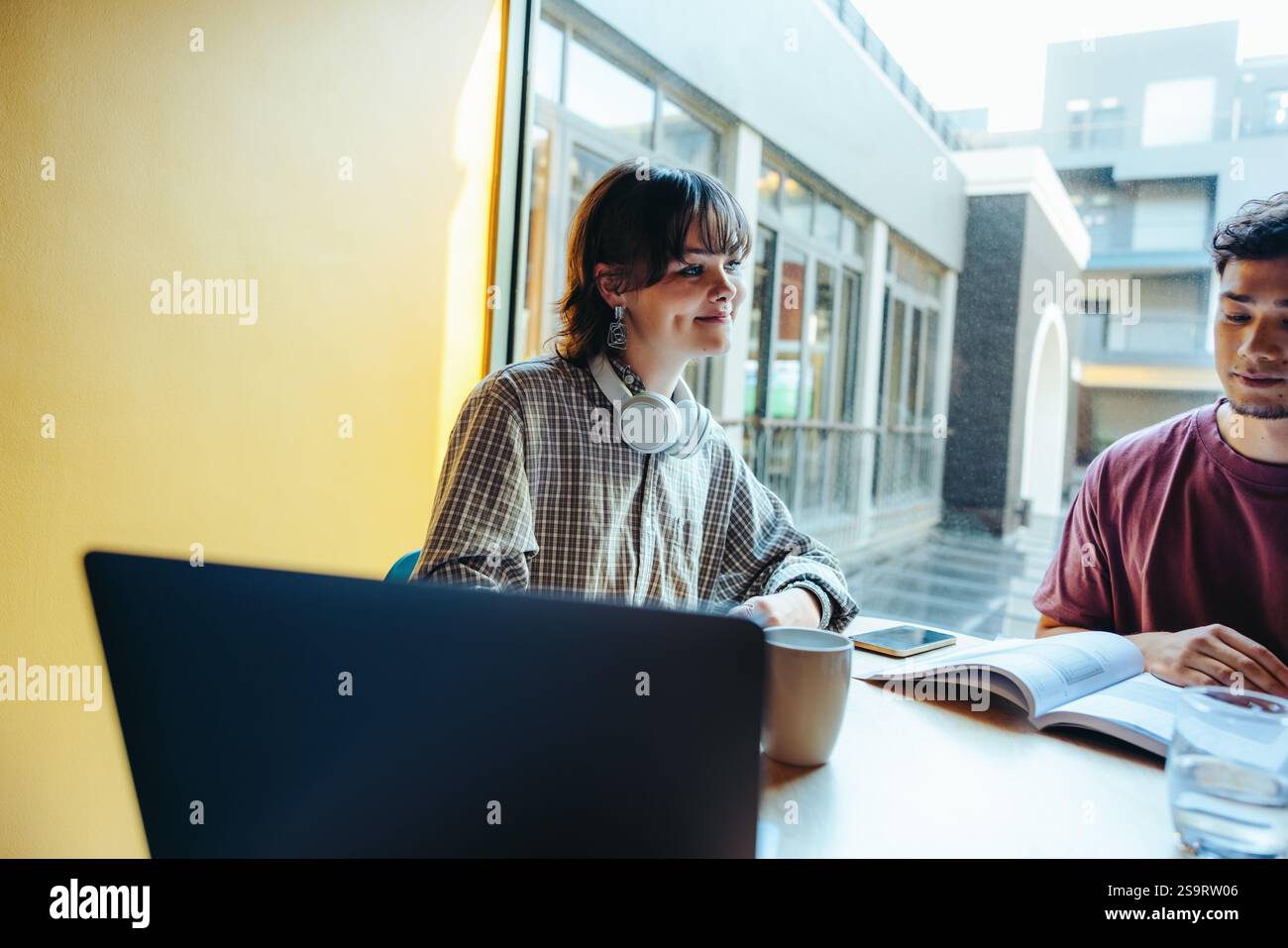 A smiling female high school student collaborates with a classmate in a ...