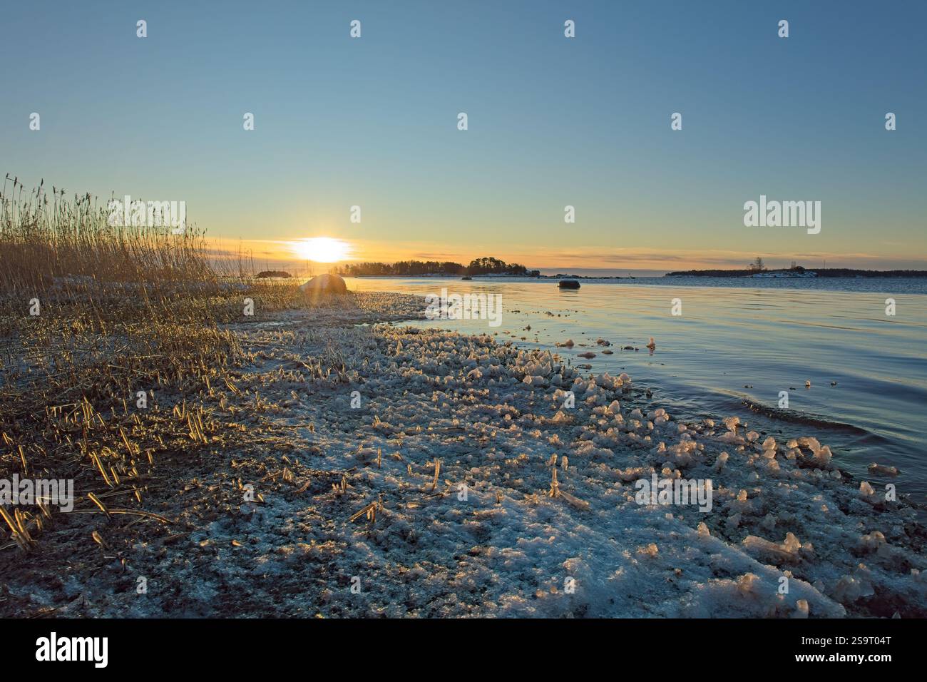 Sunrise at seashore on a cold winter day with ice on the shoreline ...