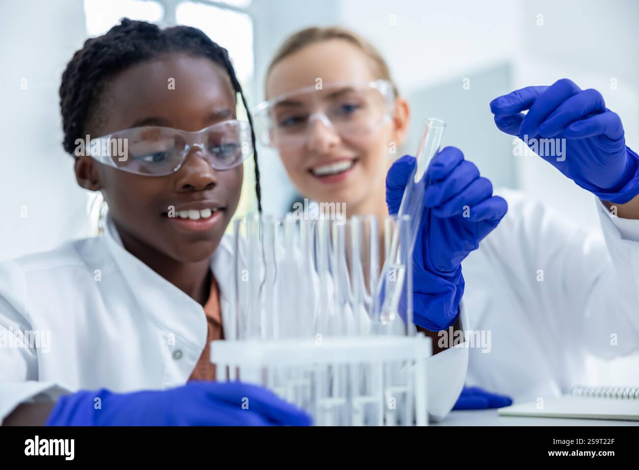 Scientist and her colleague working in lab conducting test on chemical ...