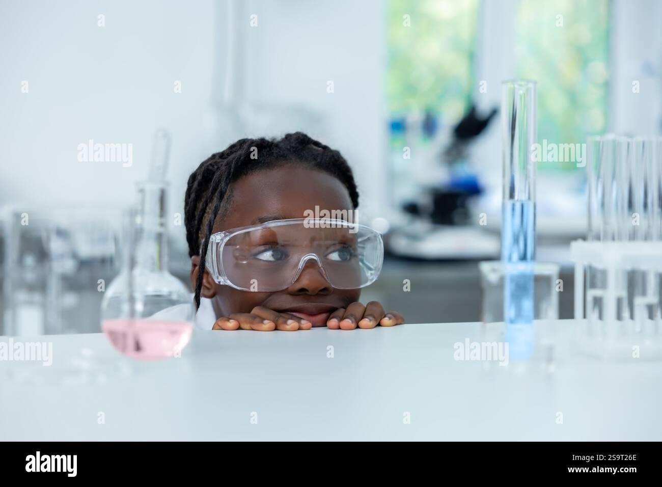 Scientist hiding behind table with petri dish and flask analyzing ...
