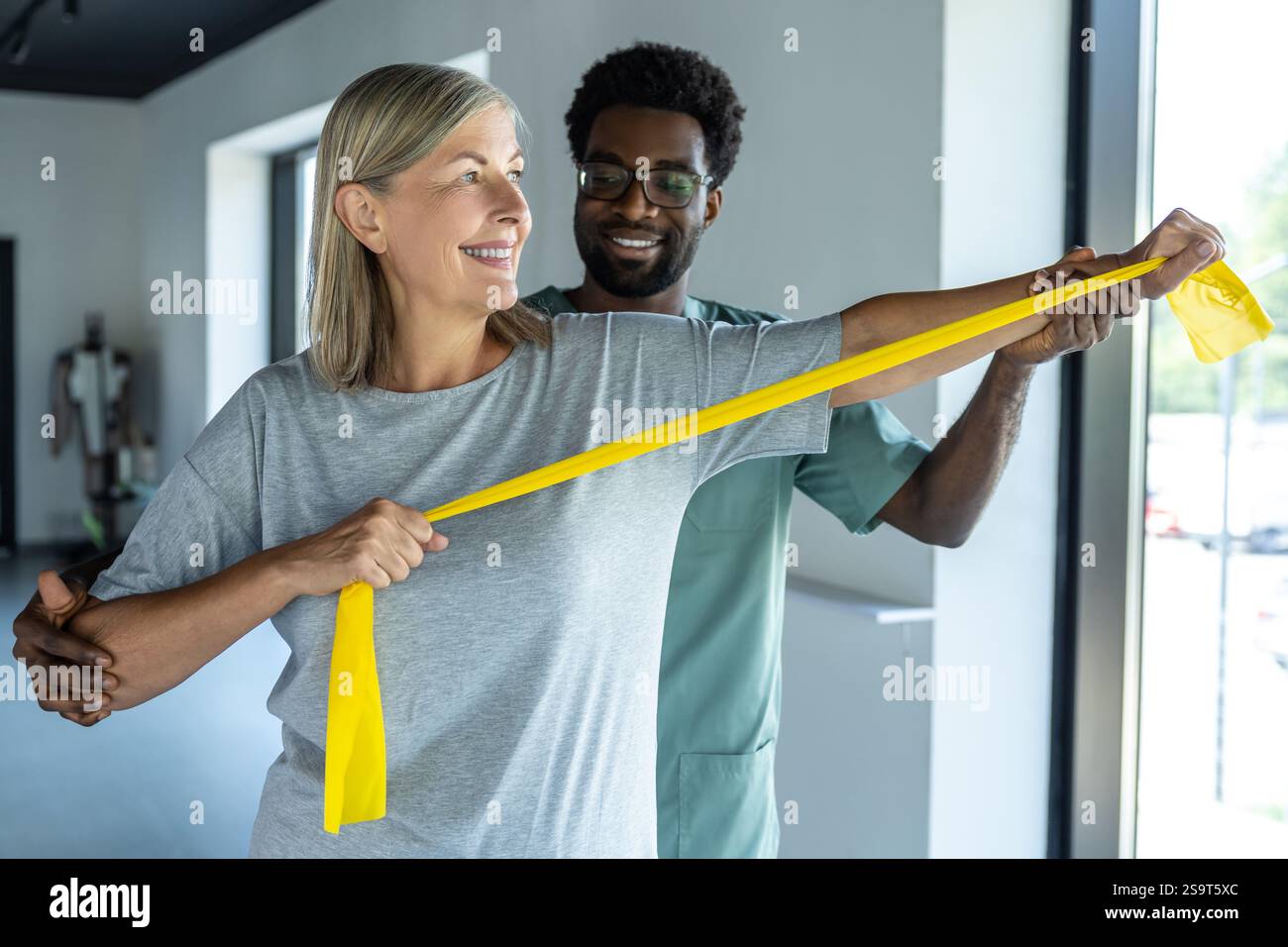 Doctor helping patient with stretching arms during rehabilitation ...