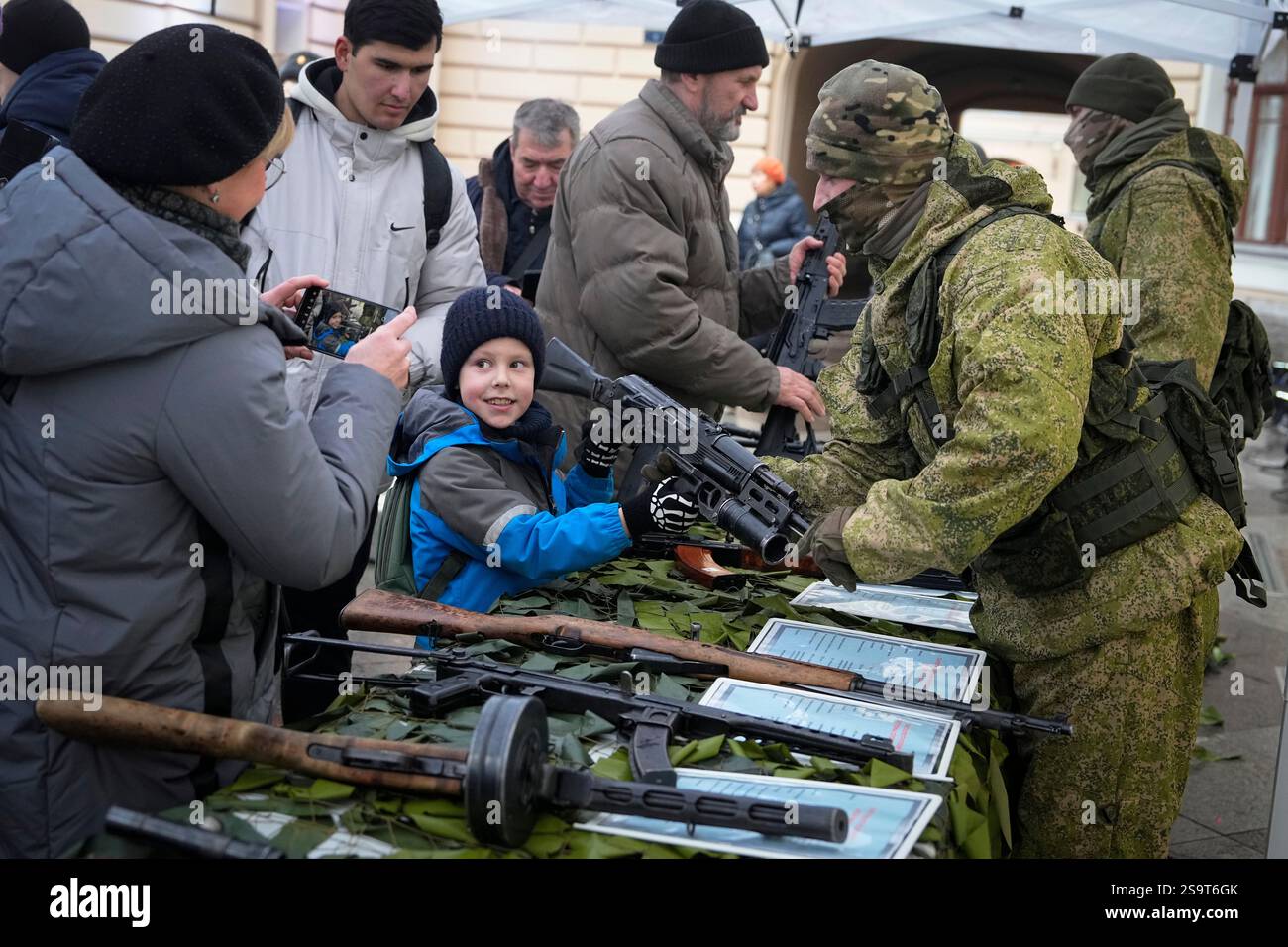 A boy poses with a Kalashnikov gun at a weapon and military equipment ...
