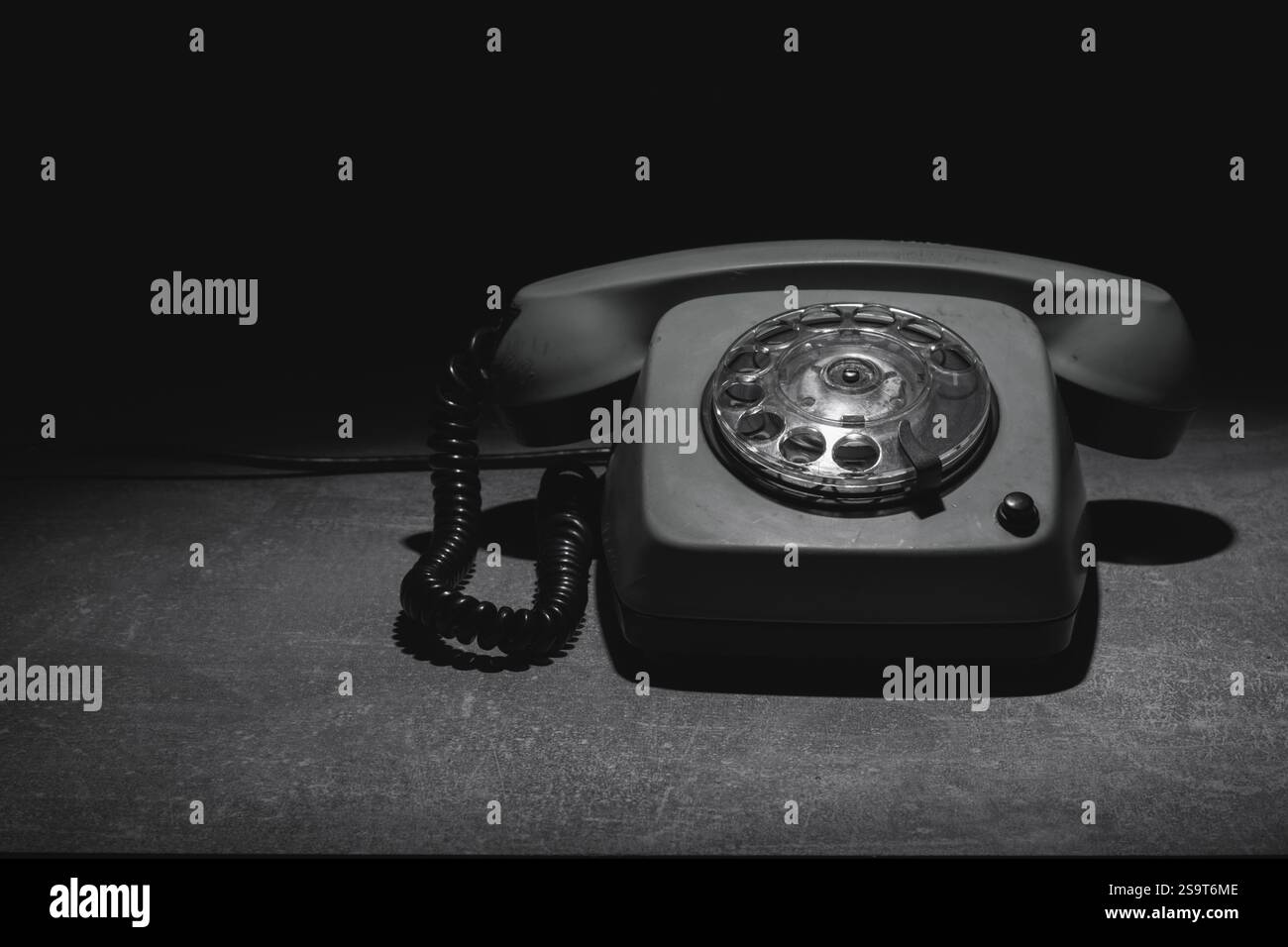 An Old Rotary Phone Rests On A Dark Surface Illuminated By Soft Light An Old Rotary Phone Rests On A Dark Surface Illuminated By Soft Light