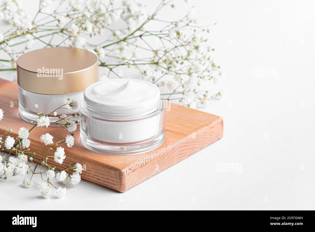 Cosmetic cream jars and gypsophila flowers on neutral white background ...