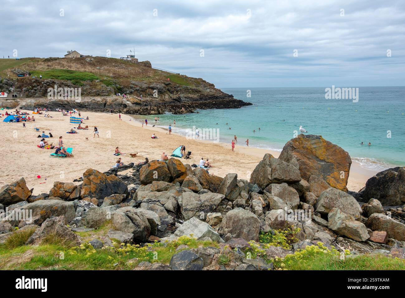 Visitors enjoy a sunny day at Porthgwidden beach in St Ives, Cornwall ...
