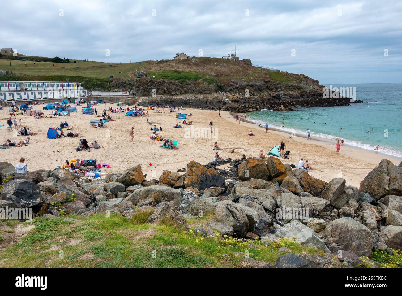 Visitors enjoy a sunny day at Porthgwidden beach in St Ives, Cornwall ...