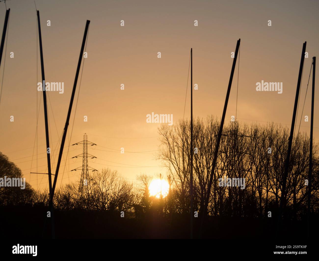Yacht masts in Abingdon Sailing Club, midwinter sunrise. Big, orange ...