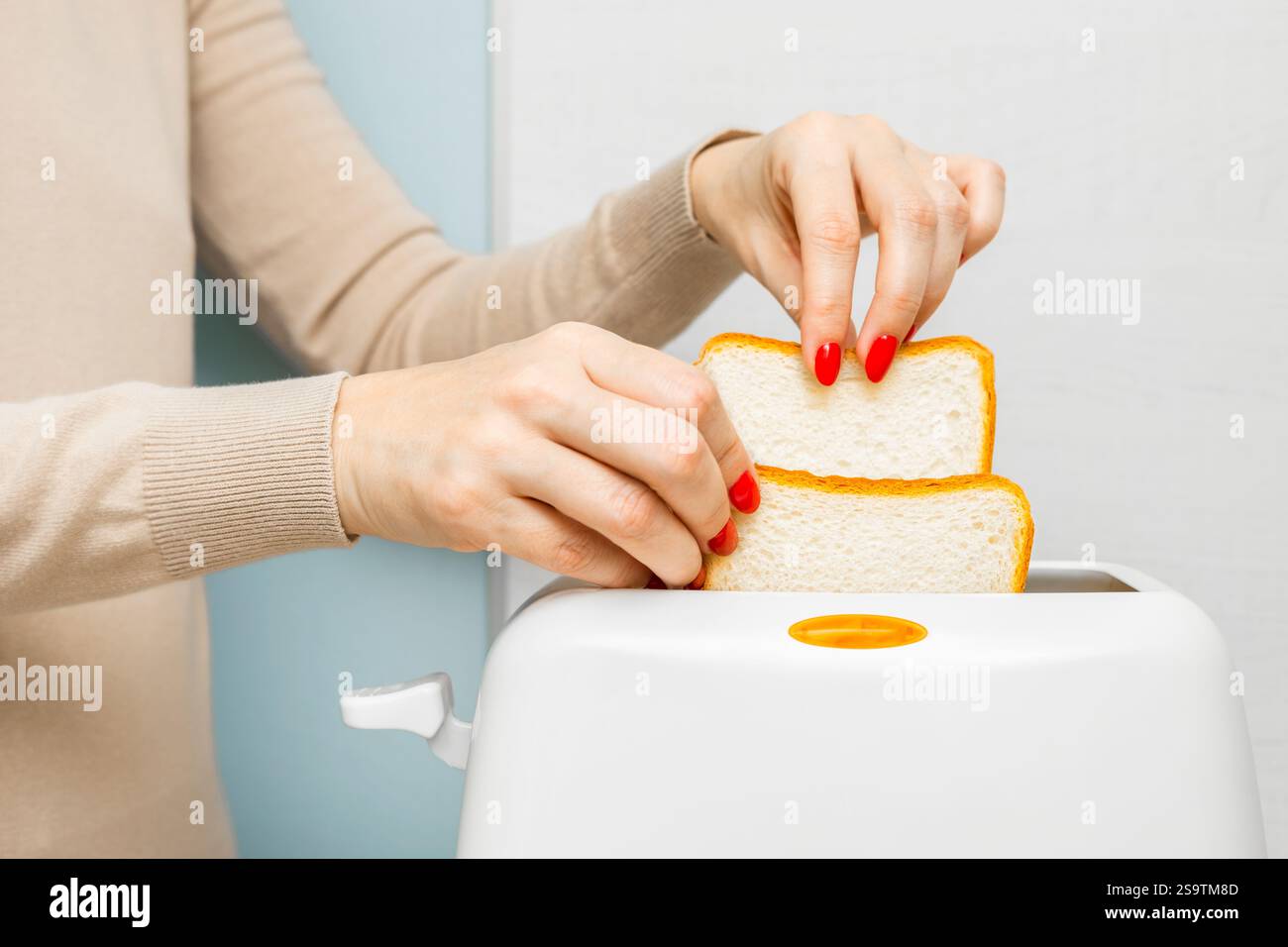 woman's hand putting bread into the toaster. housewife frying bread in ...