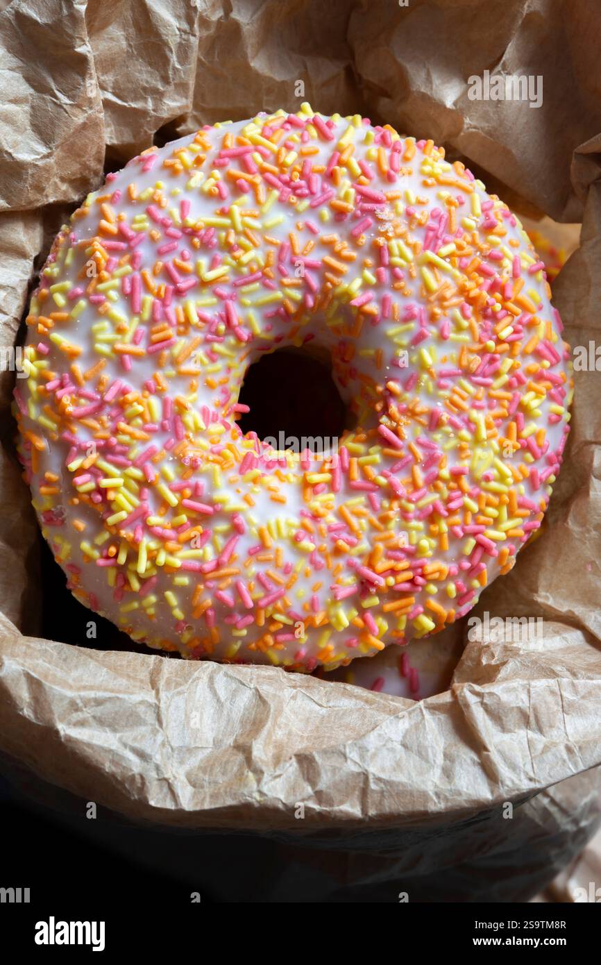 Iced ring doughnuts sprinkled with hundreds and thousands in a brown ...
