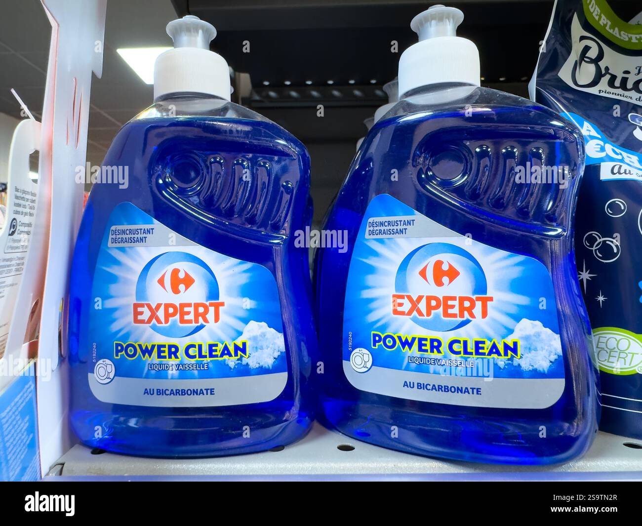 Bright blue detergent bottles lined up in a grocery aisle during ...