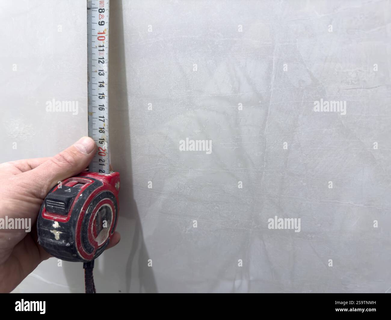 Measuring the height with a tape measure against a plain wall surface ...