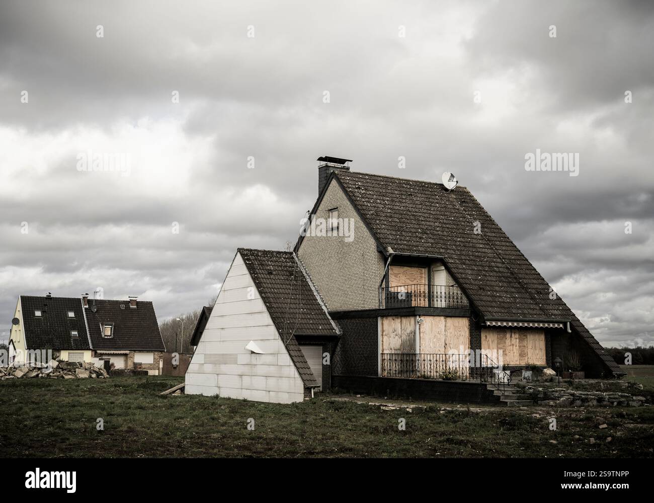 Two dilapidated houses with boarded windows stand side by side in a ...