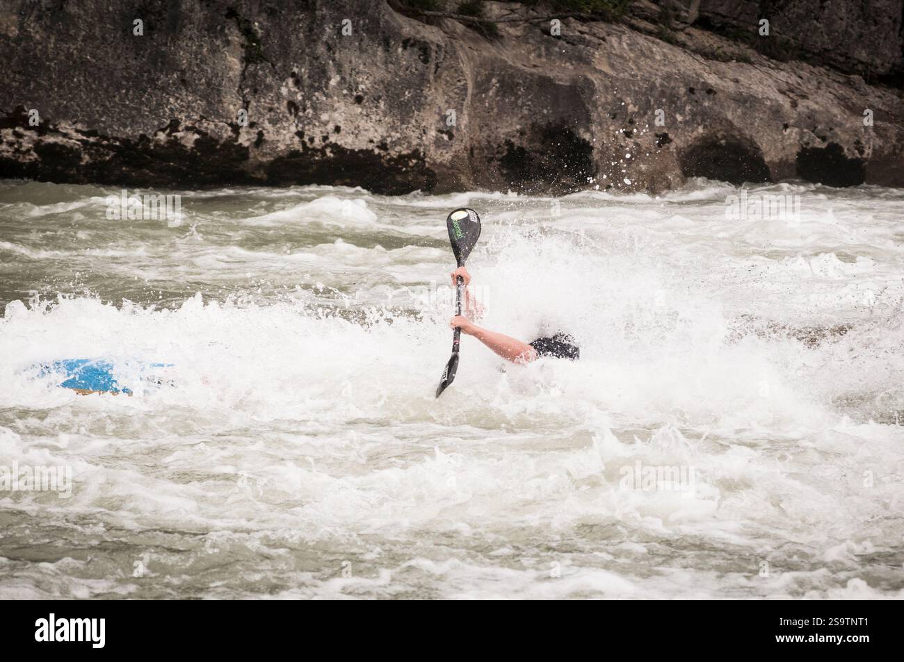 A kayaker struggles to maintain control while paddling through foaming ...
