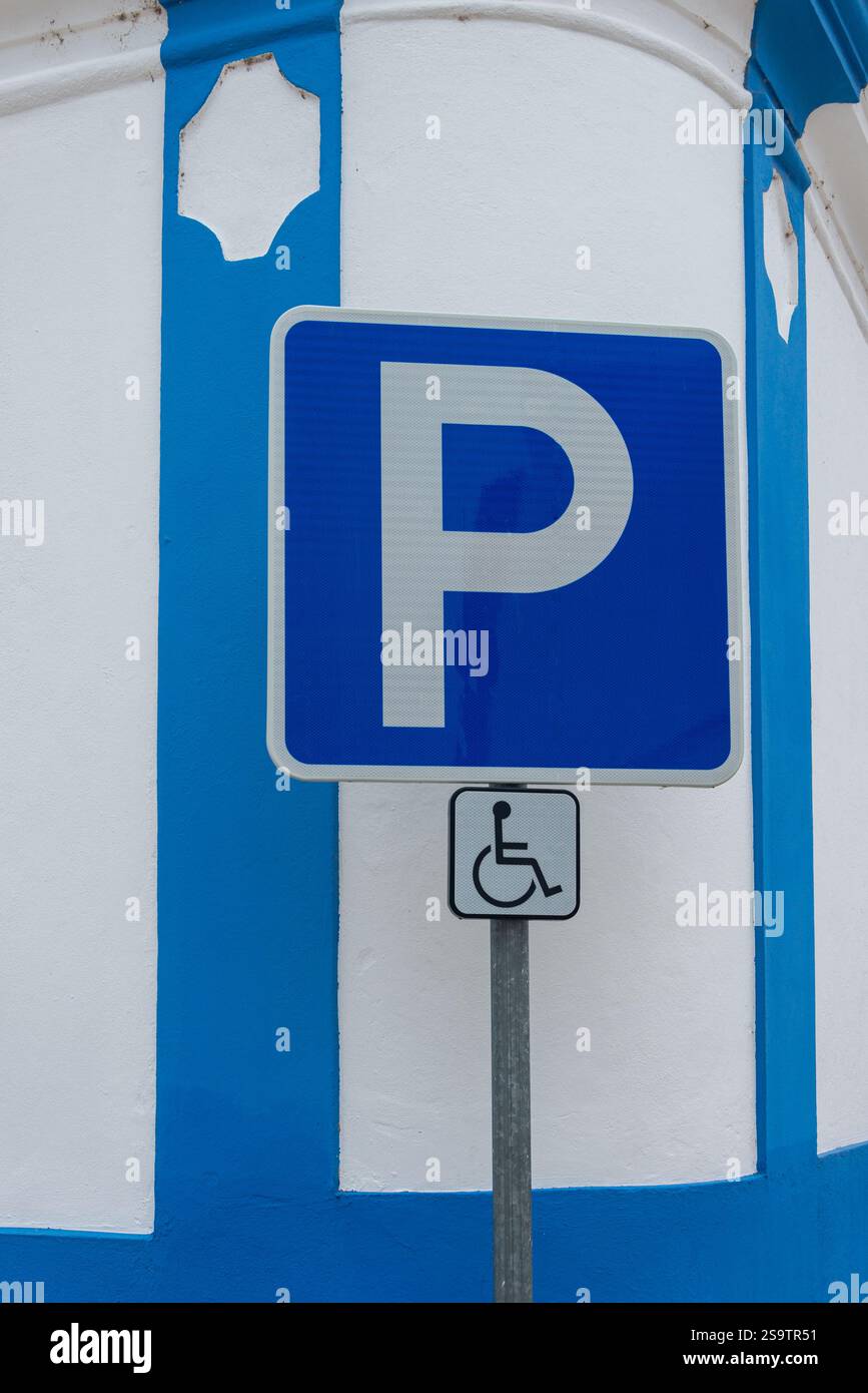 blue disabled parking sign by a blue and white wall Stock Photo - Alamy