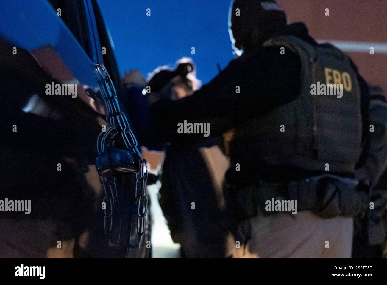U.S. Immigration and Customs Enforcement officers use a chain to more ...