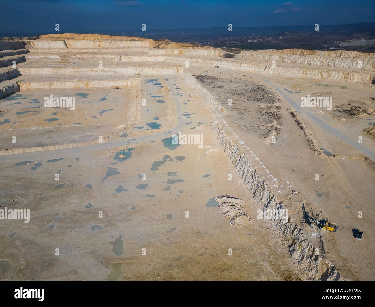 An open-pit quarry with terraced layers and heavy machinery operating ...