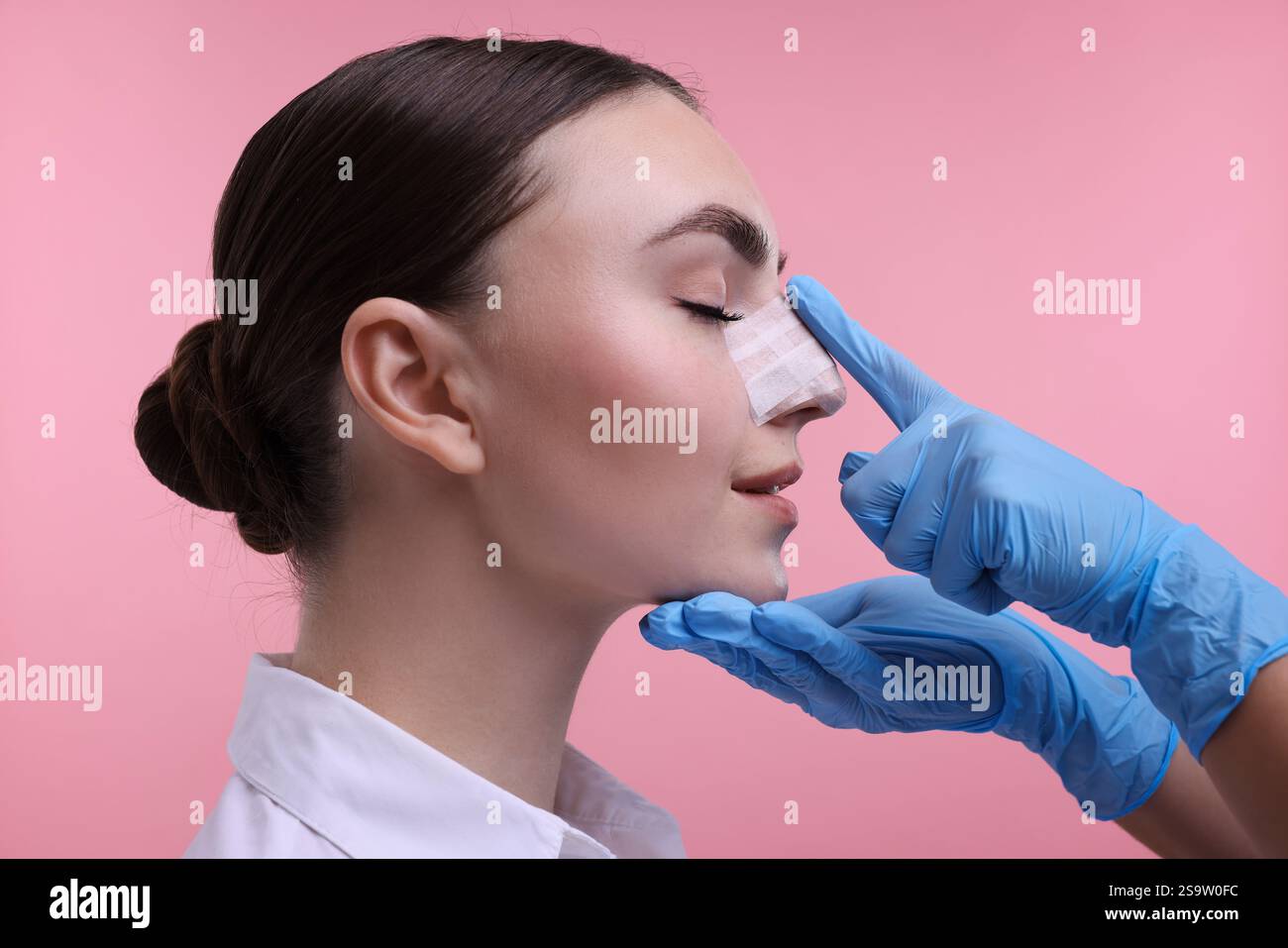 Doctor checking patient's nose after plastic surgery operation on pink ...